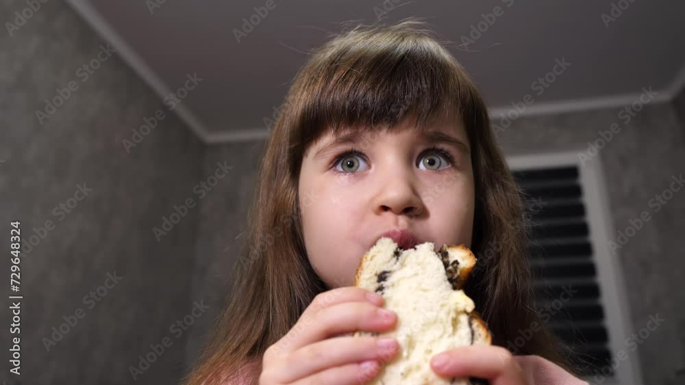 Close-up isolated portrait of a little girl eating a poppy seed bun. A ...