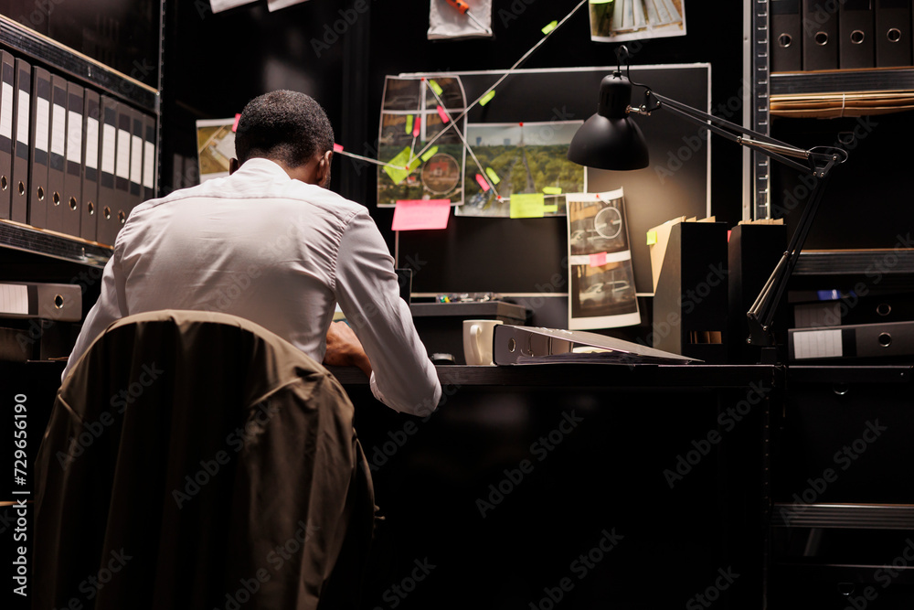 Detective sitting at workplace table and conducting investigation late ...