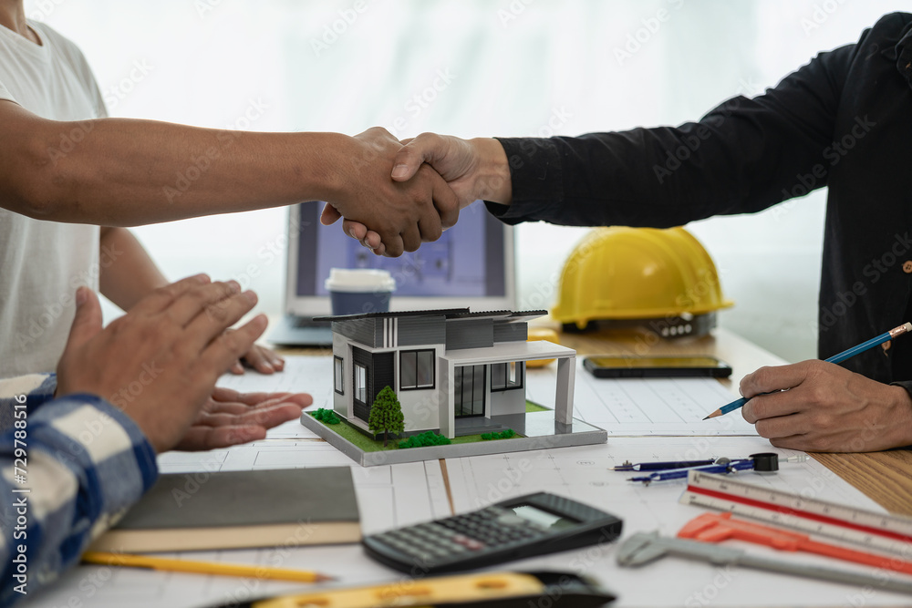 Architect and construction engineer holding hands while working for ...