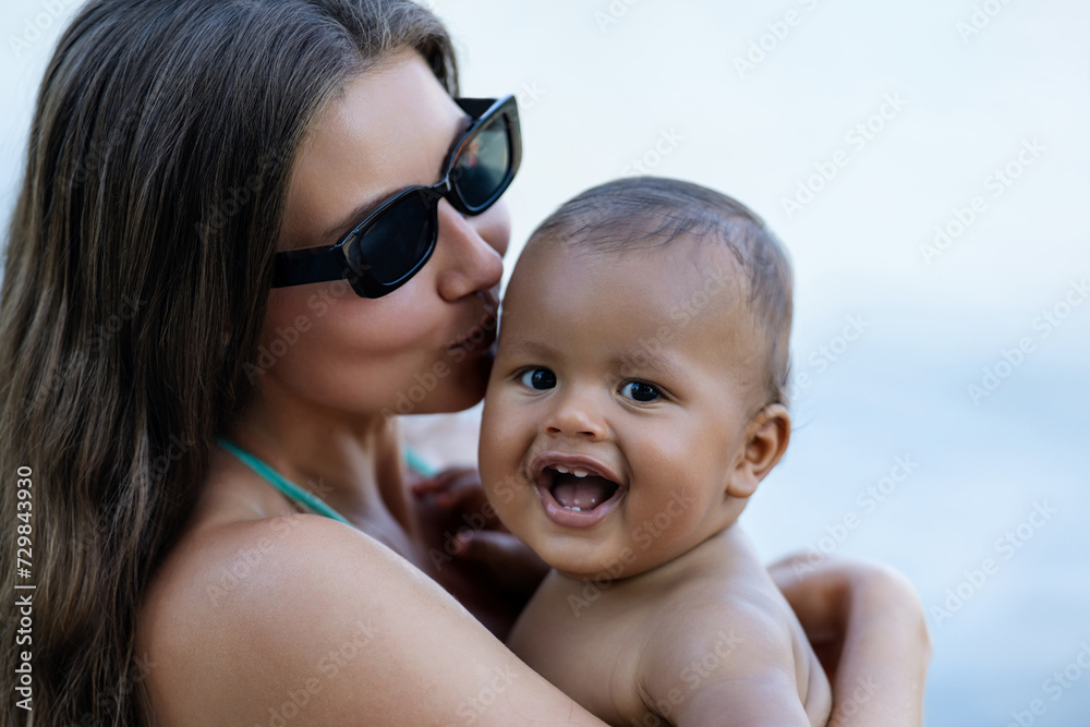 Close up portrait of mother kissing multiracial baby. Mom kiss Biracial child. Closeup face of ...