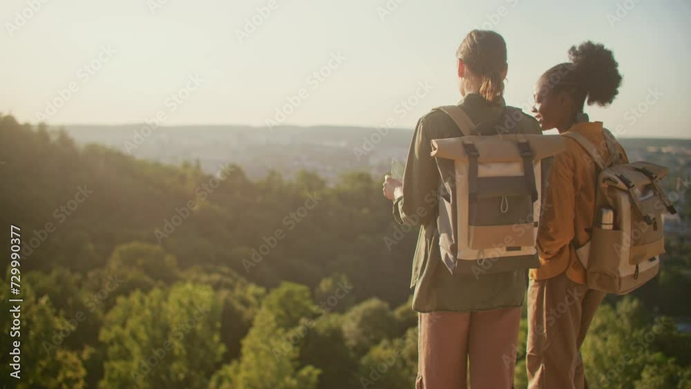 Back view of mixed-raced women wearing backpacks during walk on trail ...