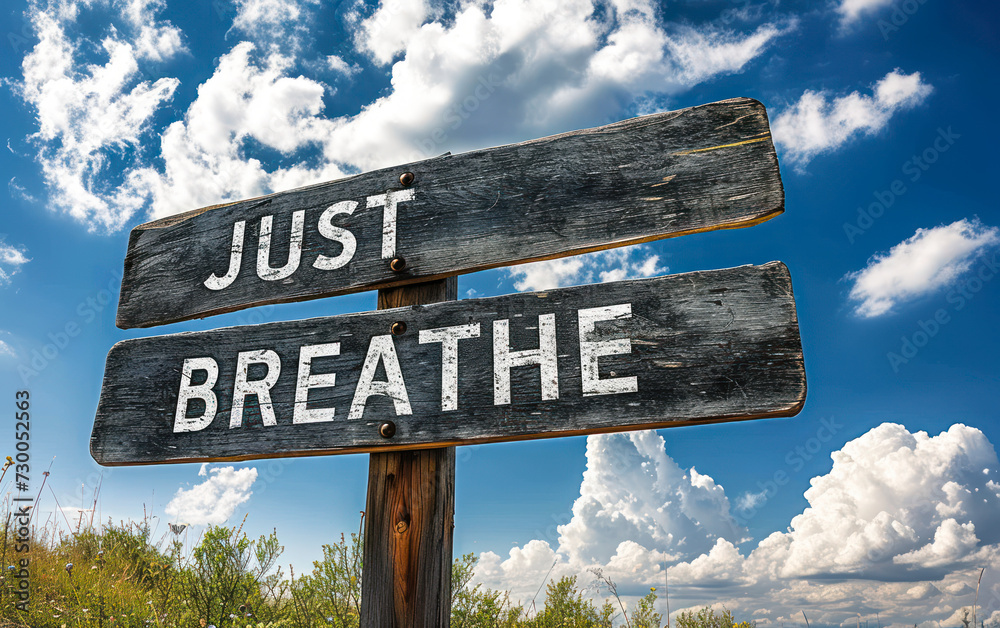 JUST BREATHE sign against a backdrop of fluffy clouds in a clear blue ...