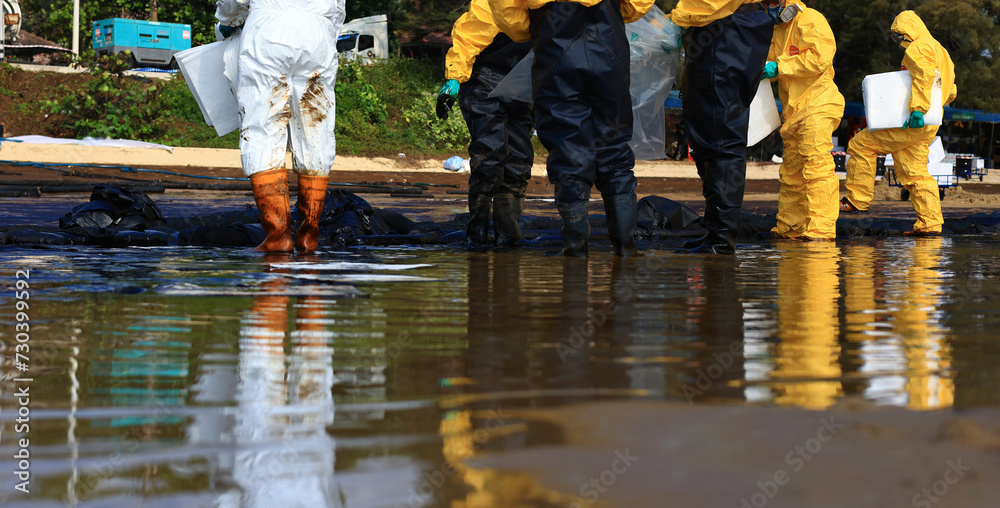 Professional team and volunteer wearing PPE clean up dirty of oil spill ...