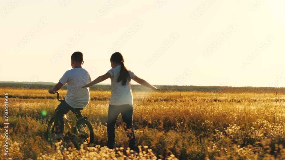 happy girl runs catching up with boy, child boy rides bicycle, son ...