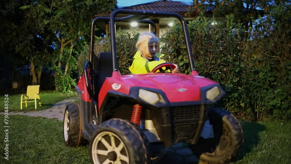 Little girl in yellow jacket drives red buggy car among plants on ...