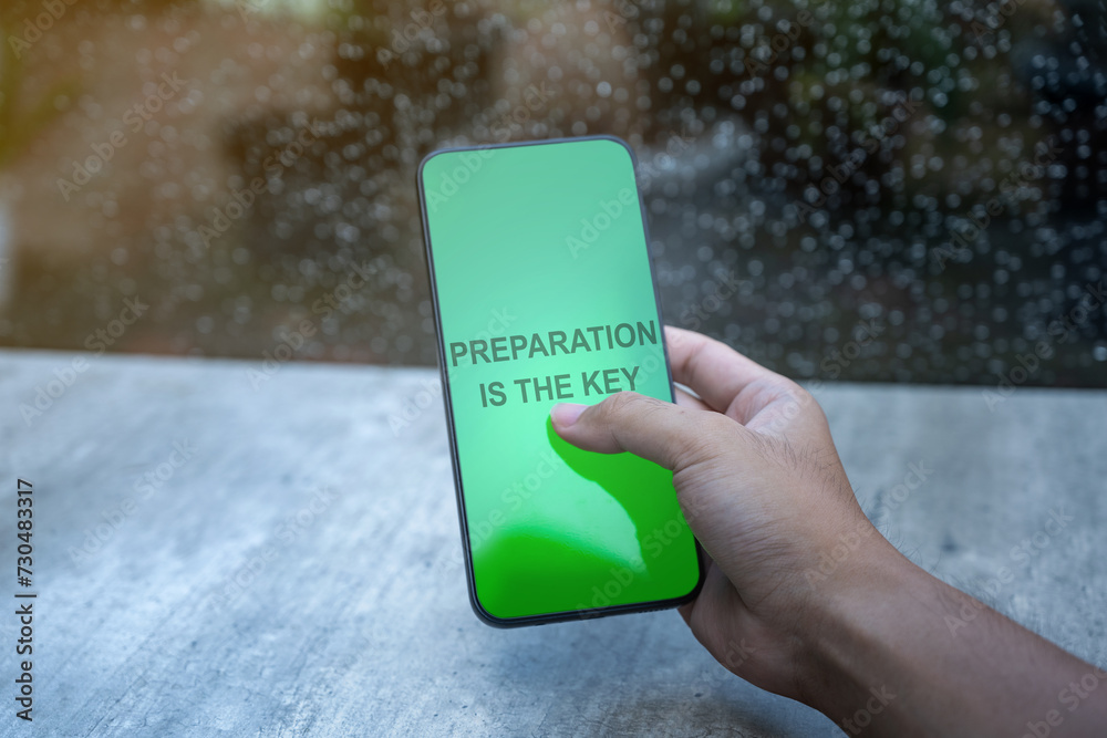Human hand holding mobile phone with 'Preparation is the key' text on ...