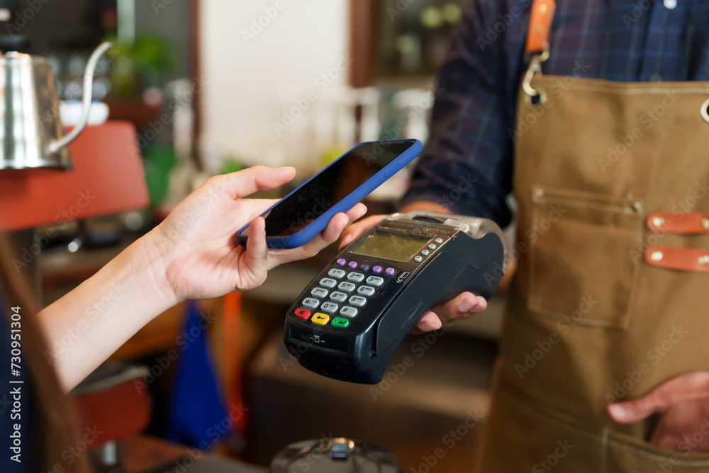 A beautiful Asian female customer comes use cafe holds cell phone scan ...