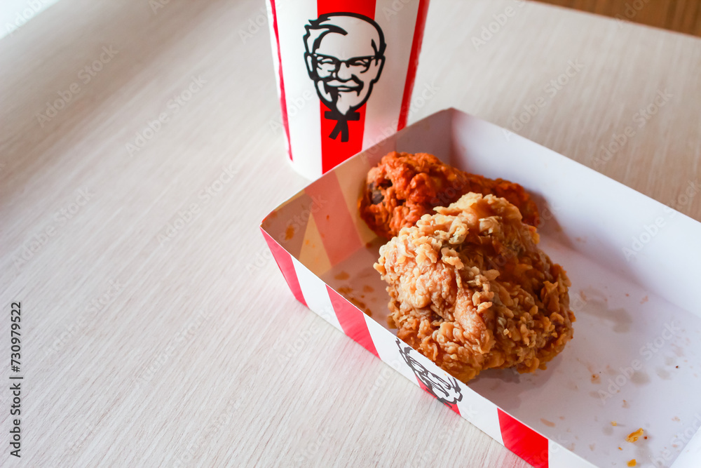 Bangkok, Thailand - January 07 2024 - Two pieces of KFC fried chicken on a paper plate and a ...