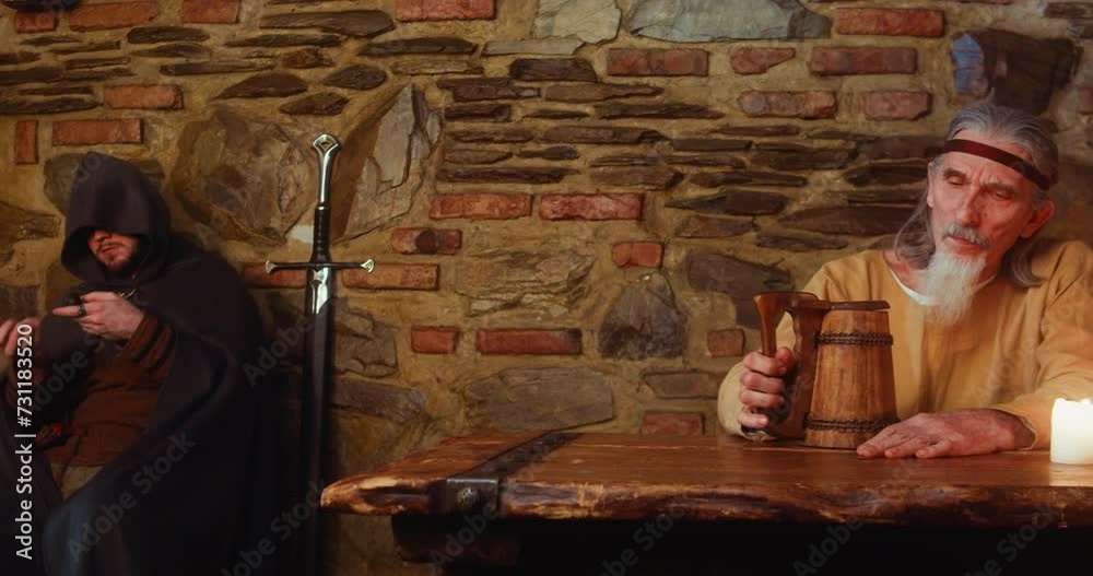 Waitress pours drink and takes silver coin in medieval tavern. Various ...