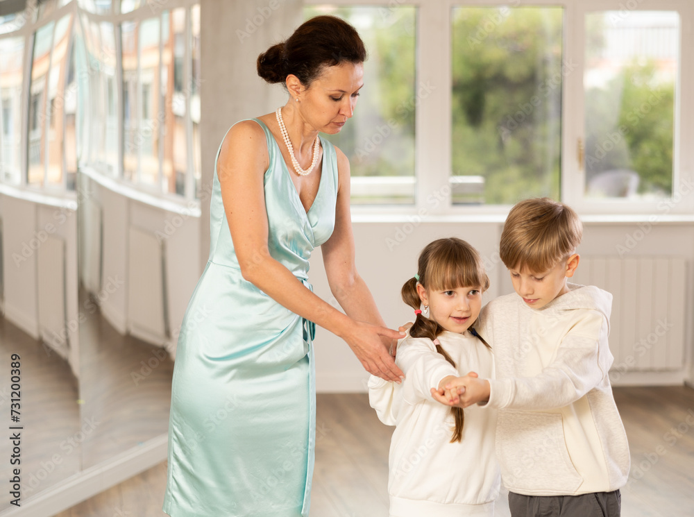 In sunlit dance studio, professional female instructor adjusting ...