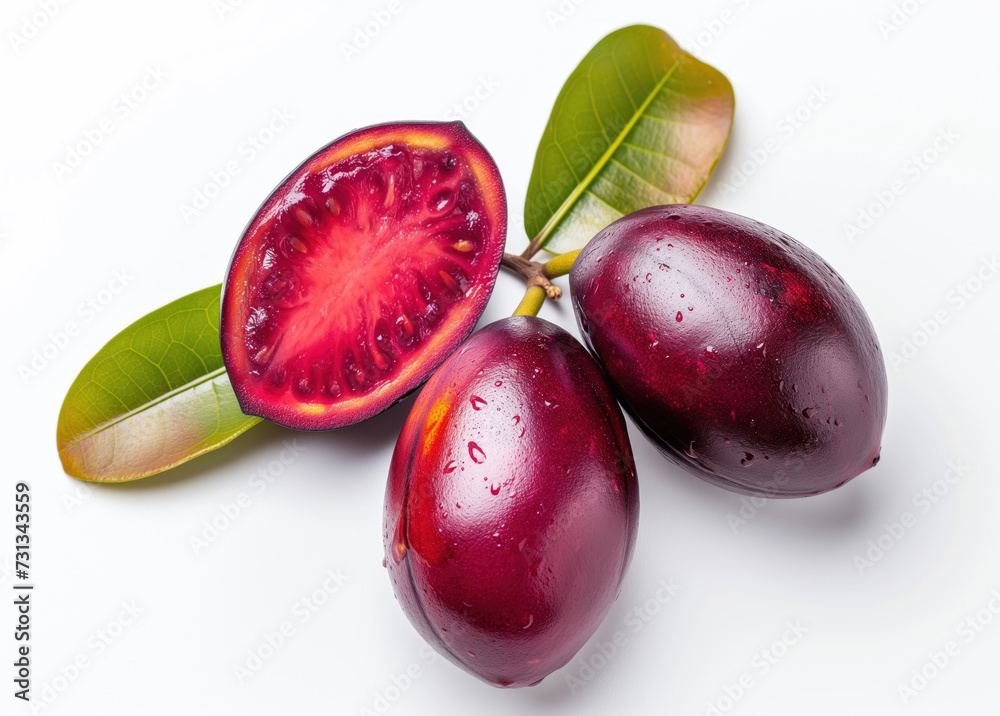 A close-up view of a ripe miracle fruit, whole and sliced open to ...