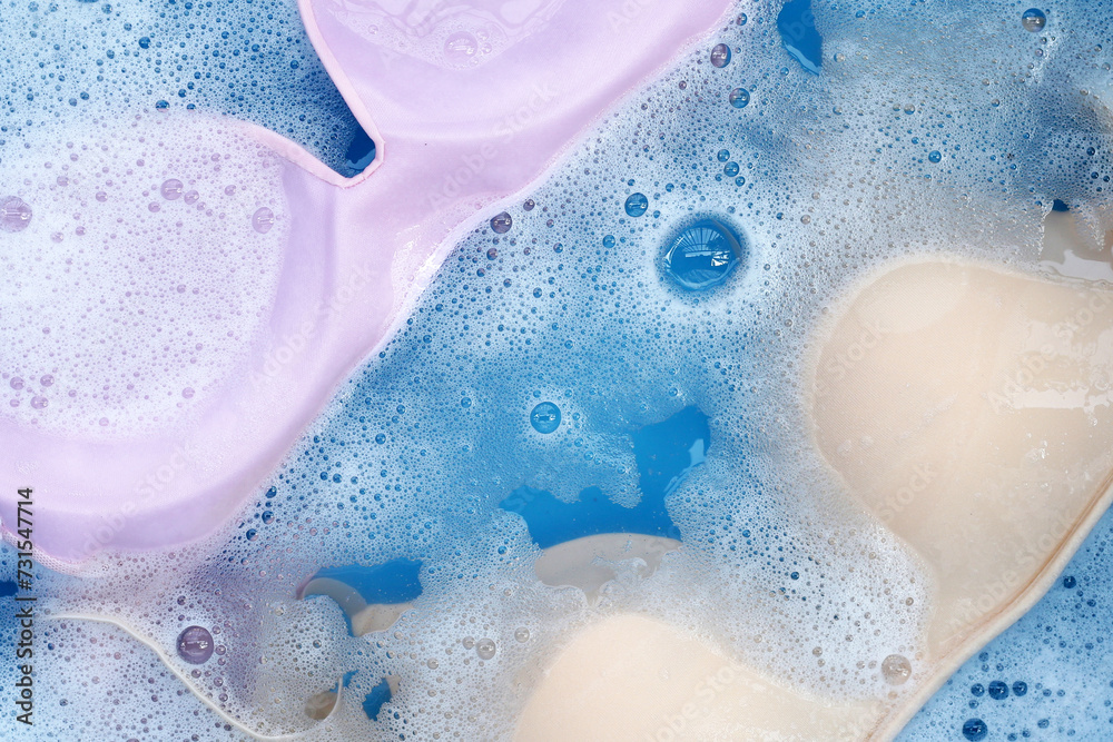 Lady bra soaked in water dissolved detergent with white foam bubble ...