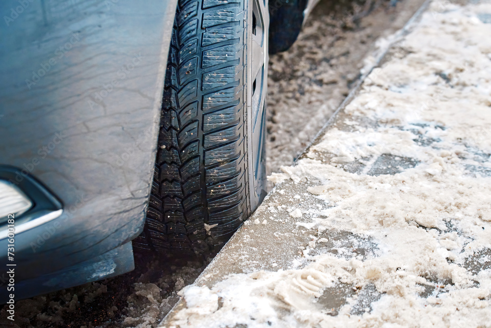 Car wheel parked close to the curb on parking lot. Wheel sticking to ...