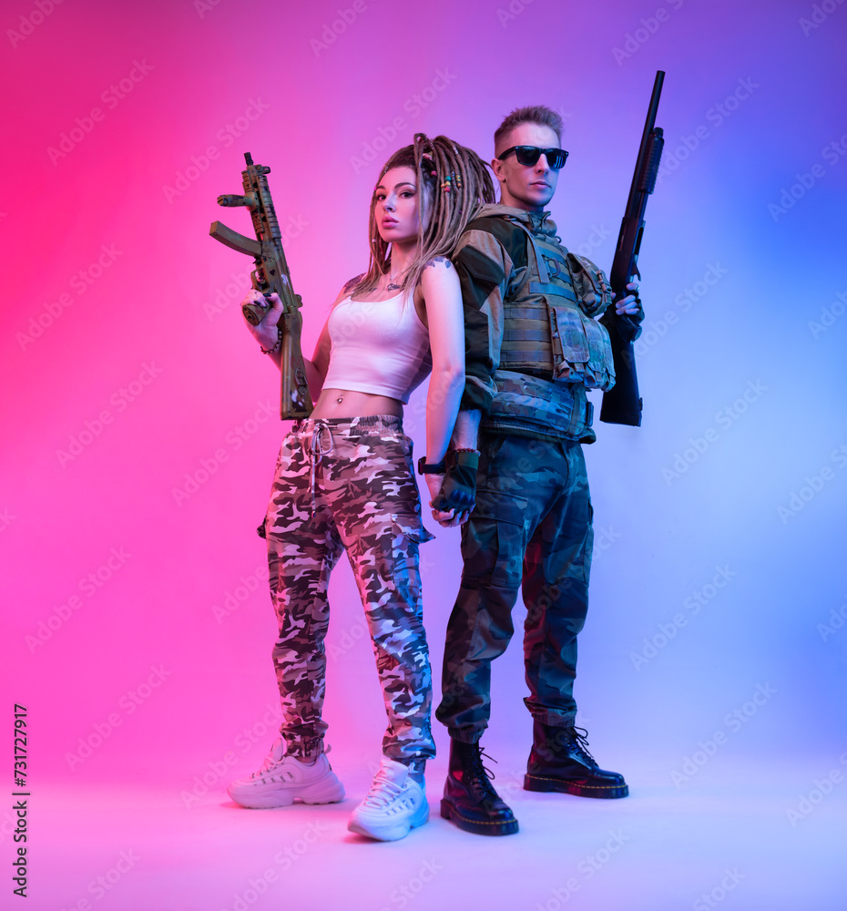 daring stylish girl with an automatic rifle and a guy in military ...