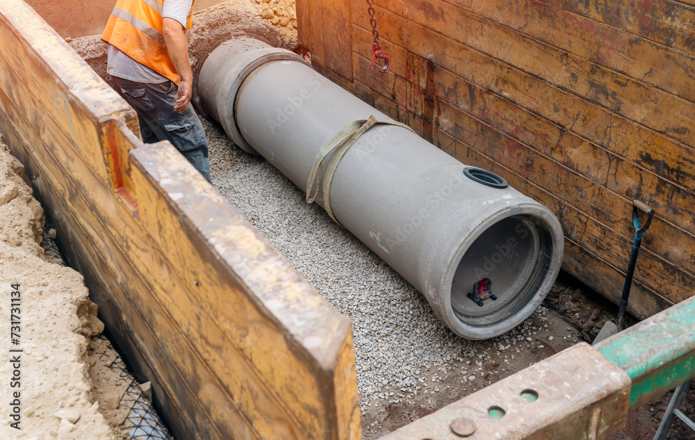 Builder installing big diameter concrete drainage pipe protected by ...