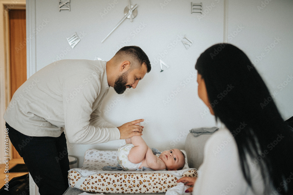 Father changing diaper of baby boy by mother in bedroom at home Stock ...