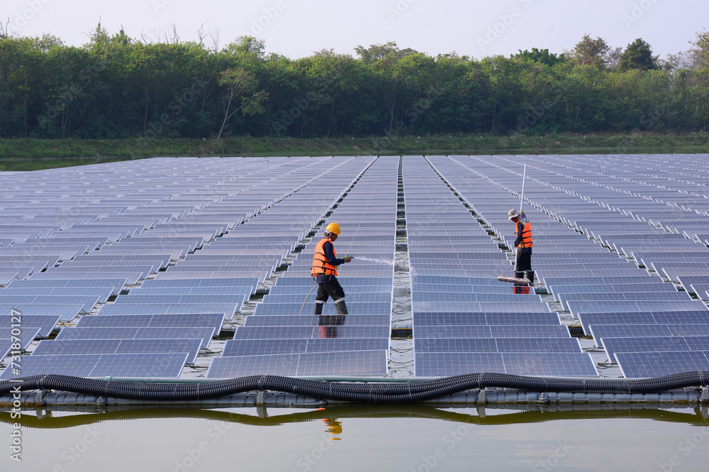 Professional workers cleaning and inspecting solar panels on a floating ...