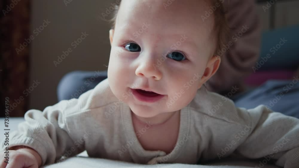 A cheerful baby with sparkling blue eyes and a tuft of light hair ...