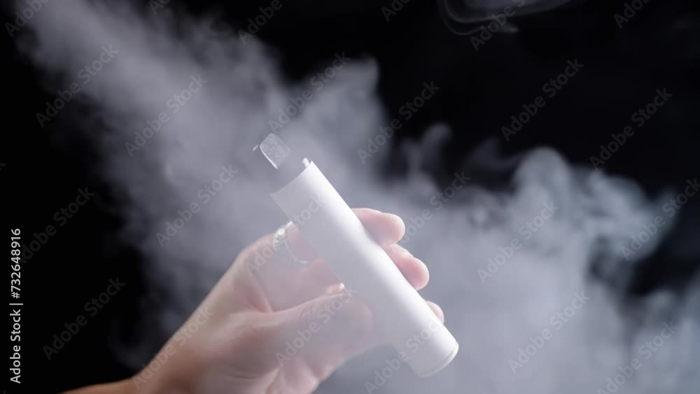 Close up, Smoking a Vape or E-cigarette in a Dark Room on a Black ...