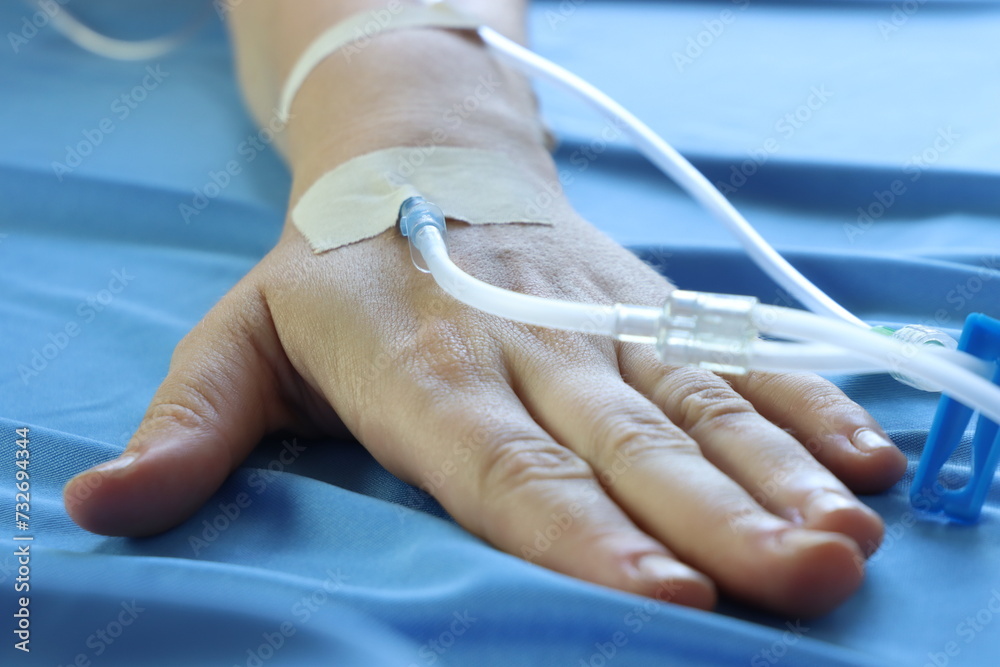 Woman patient in the bed with IV acess an pulse oximeter sensor in the ...