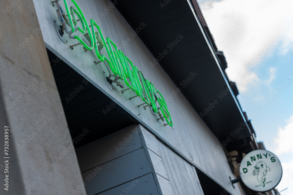 glancing up at a retro neon sign of Danny's Pizza Tavern, a pizza ...