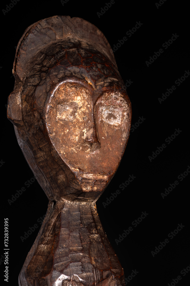 An African male figure portrait carved in wood isolated on black ...