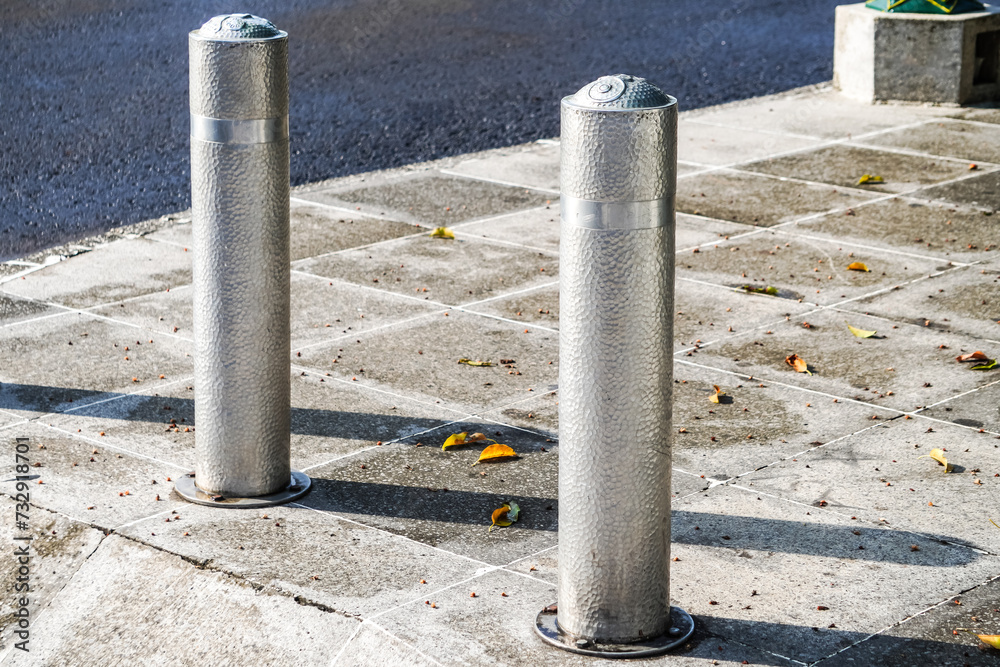 Metallic long inground bollard pole barrier between asphalt road and ...