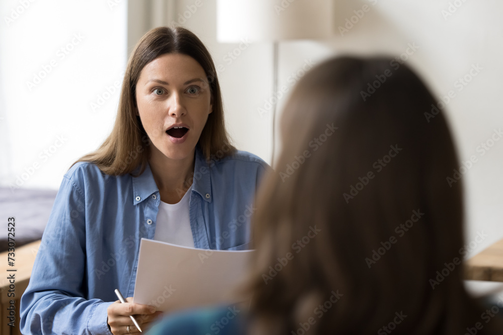 Shocked entrepreneur woman holding paper document, staring at female ...