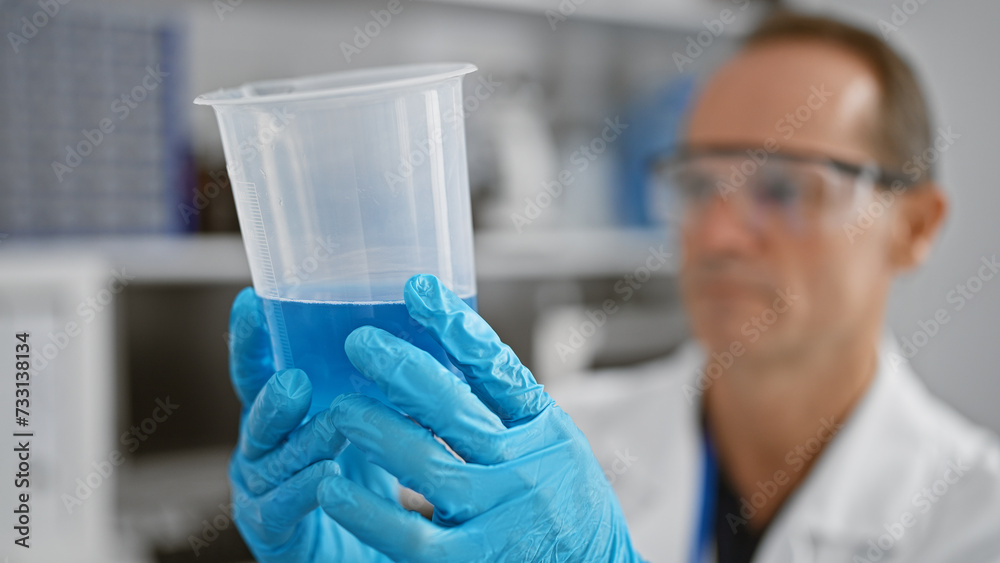 Serious, middle age man-scientist, diligently measuring liquid in a ...