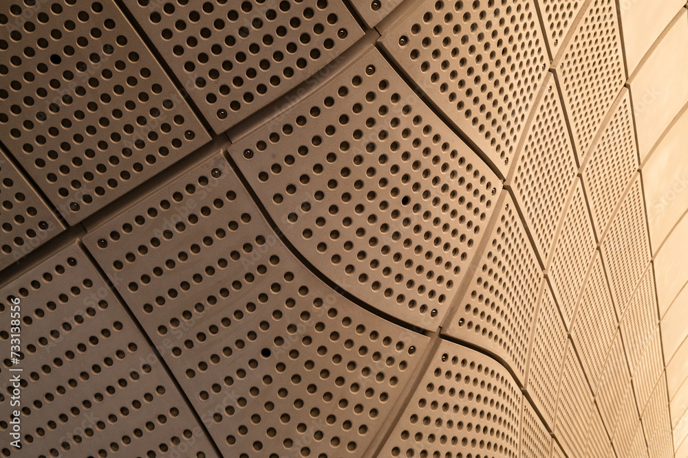 Curved and perforated contemporary wall panels bend around a structure ...