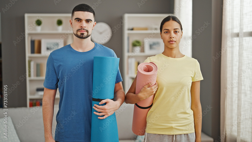 Stunningly athletic couple hold yoga mat, standing in serious ...