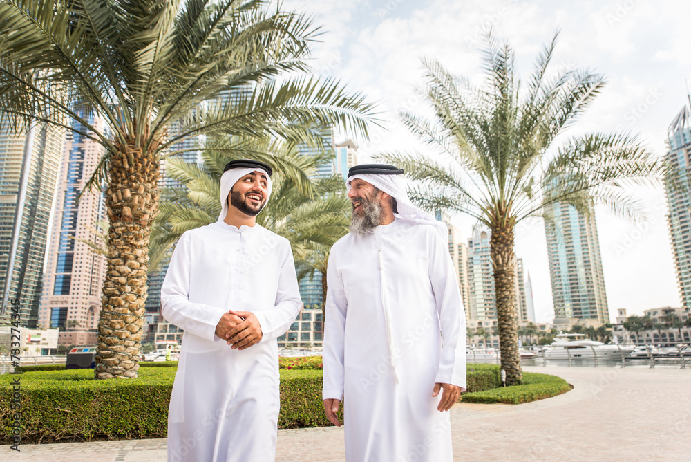 Arab businessmen wearing traditional emirati kandora meeting outdoors ...