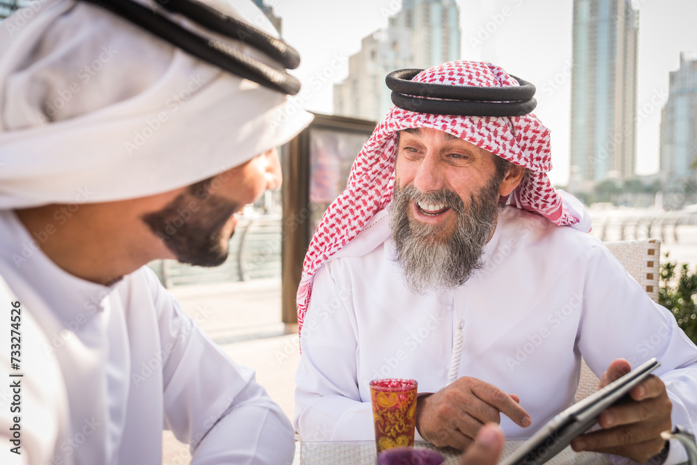Arab businessmen wearing traditional emirati kandora meeting outdoors ...