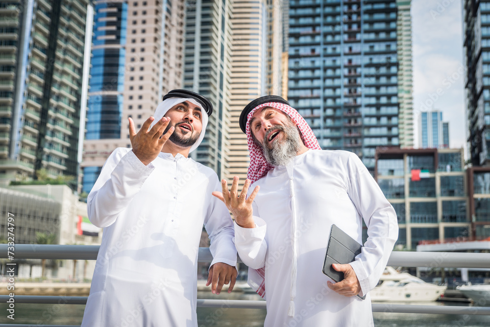 Arab businessmen wearing traditional emirati kandora meeting outdoors ...