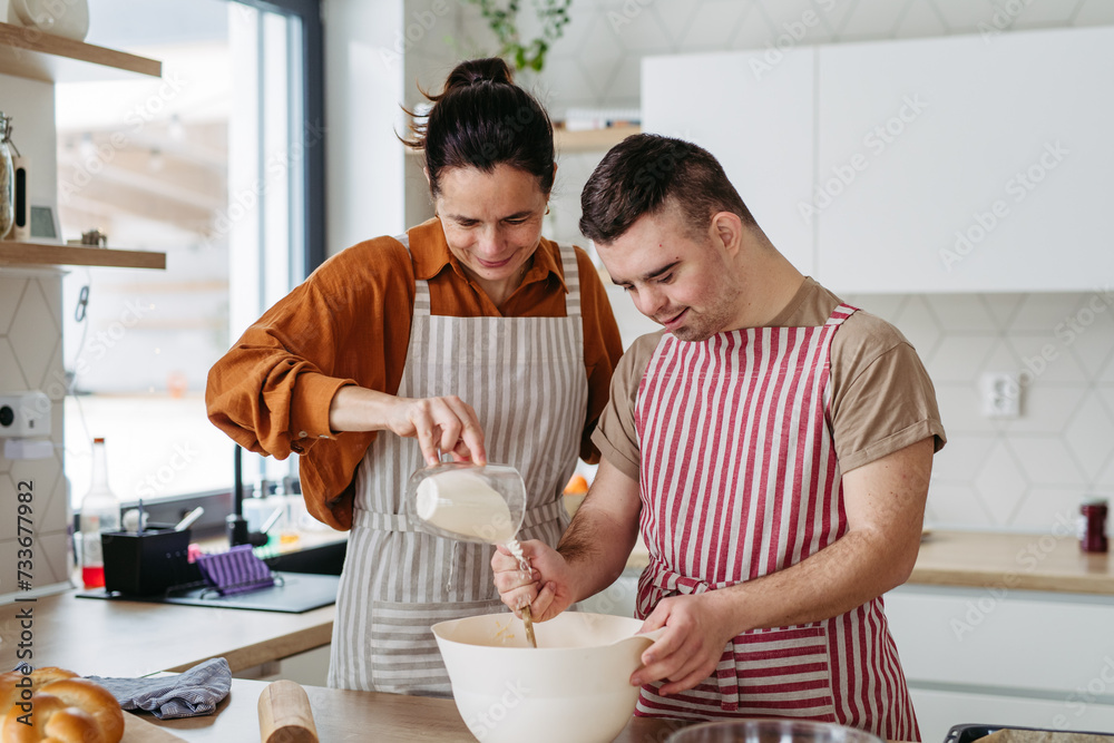 Young man with Down syndrome preparing breakfast with his mother at ...