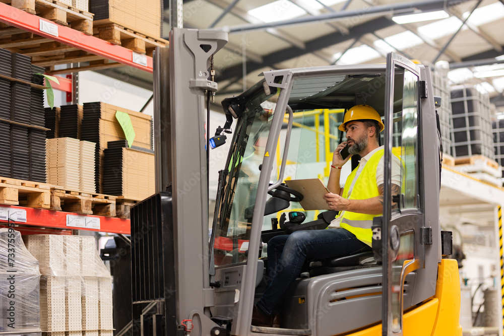 Warehouse forklift driver holding smartphone, phone calling. Warehouse ...