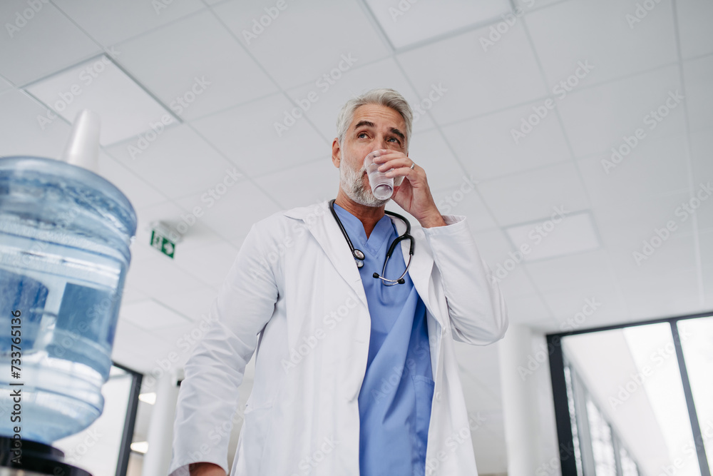 Handsome doctor taking a break during work shift at hospital, drinking ...