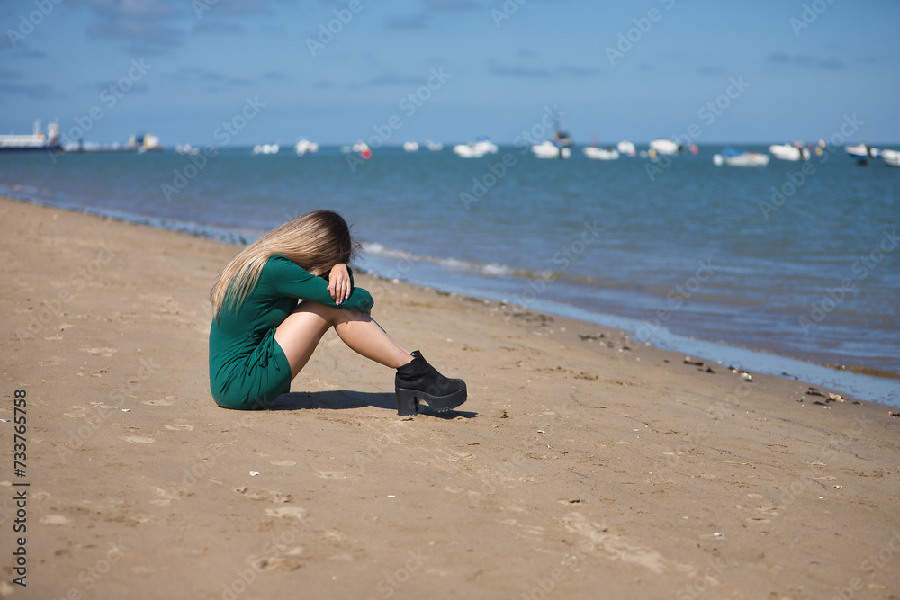 Young, beautiful, blonde woman, wearing a green dress, sitting on the ...