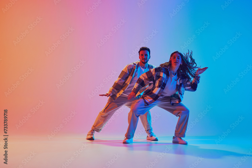 Full length portrait of coordinated dance pair dancing in neon lighting ...