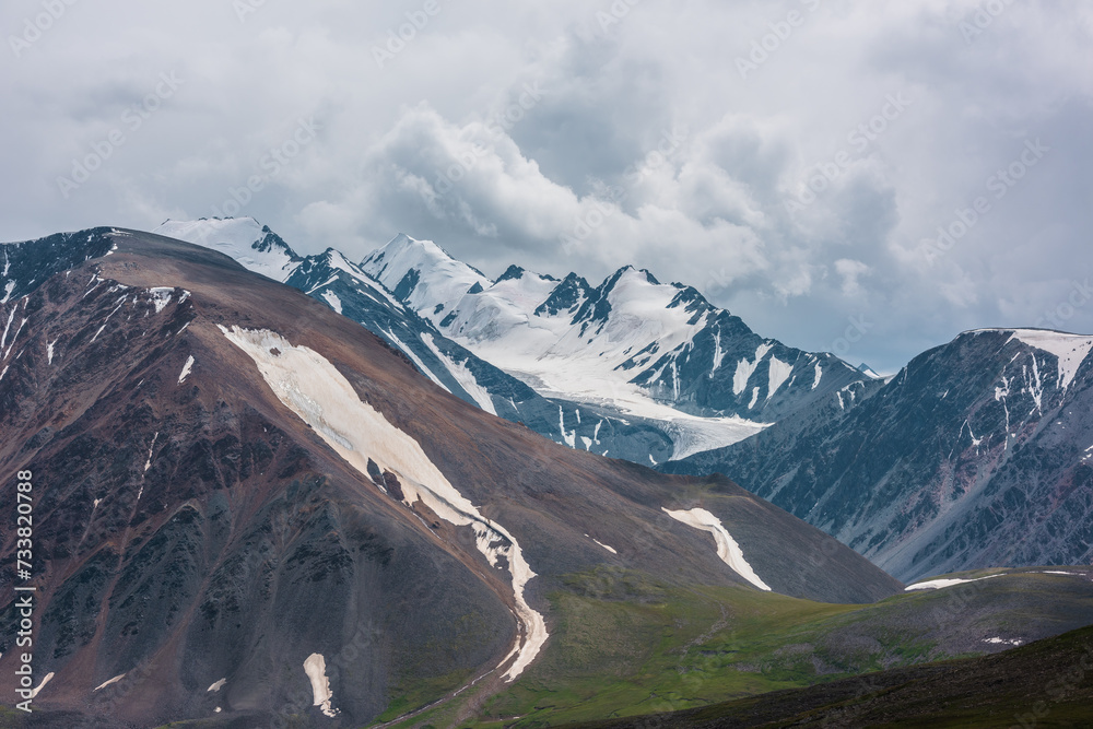 Dramatic view to large rock mountain range with snow-capped pinnacle in ...