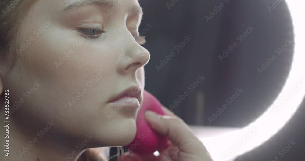 Portrait of a pretty girl, makeup artist applies makeup and toning of ...