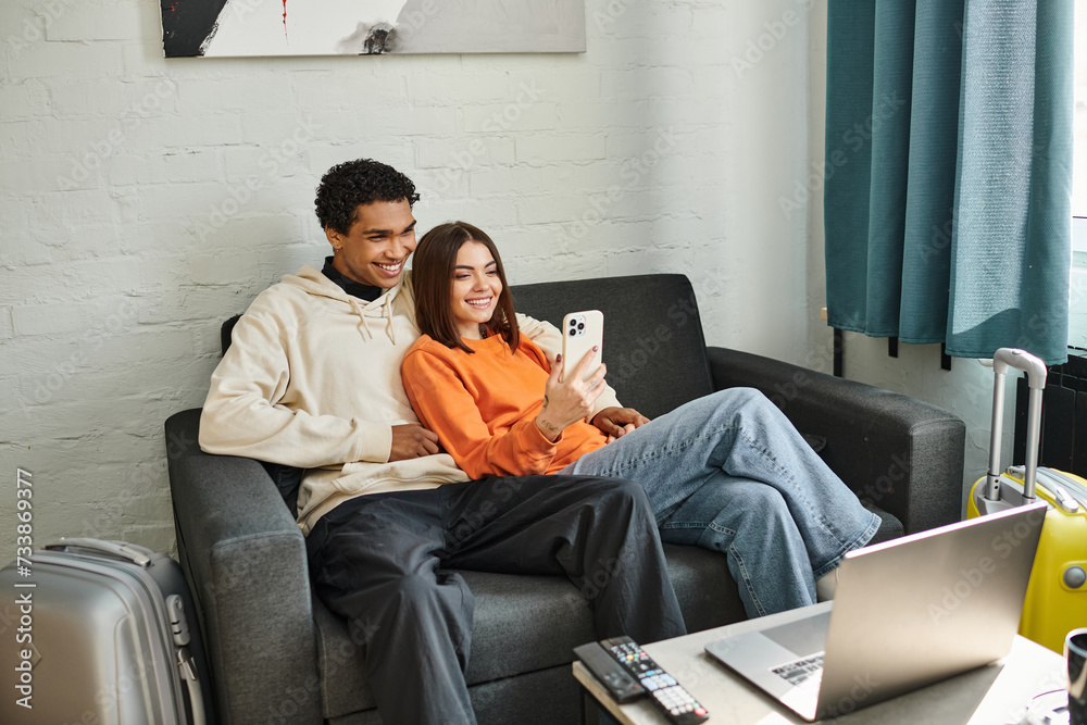 happy diverse couple shares a cozy moment, scrolling through phones on ...