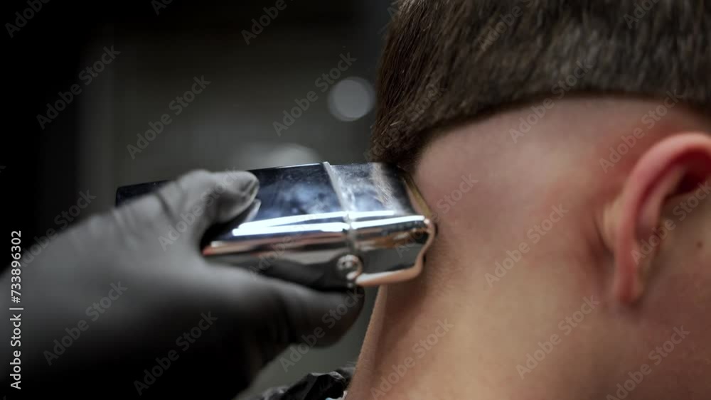 Professional barber clips clients hair in salon. Sharp detailed close ...