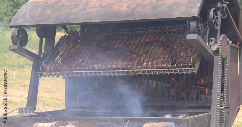 Fire roasted whole lamb. Lamb on a skewer. The spit-roasted lamb is ...