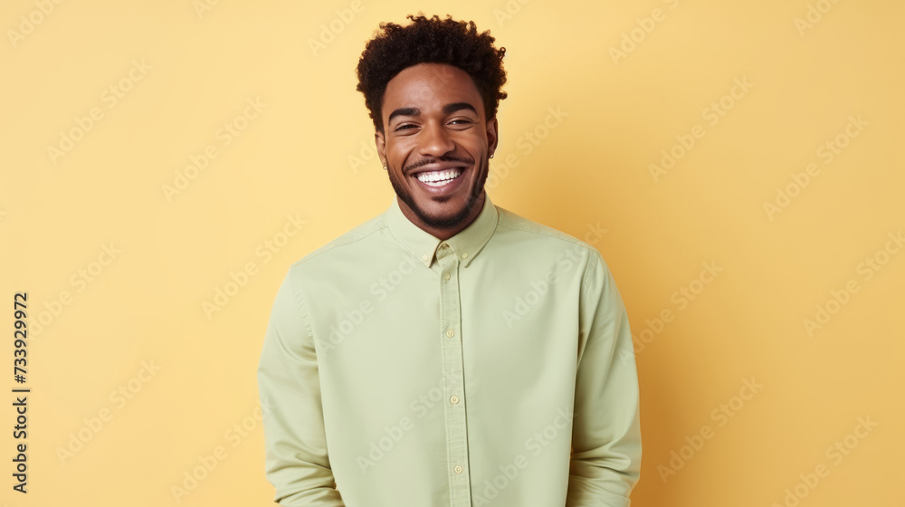 Happy young man with a bright smile standing against a yellow ...