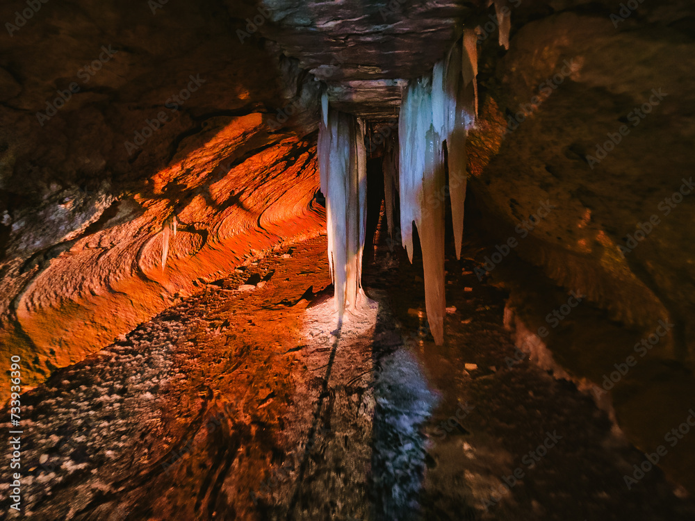 The illuminated frozen waterfall of underground waters under the arches ...