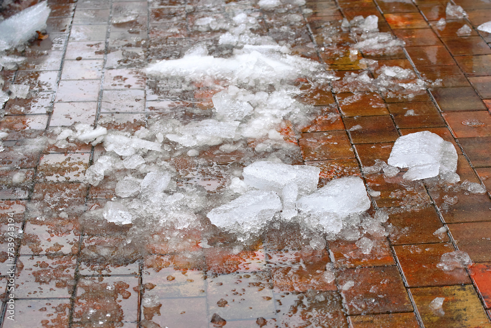Pile of ice and snow melting on paving slabs, ice thaw on sidewalk. Wet ...