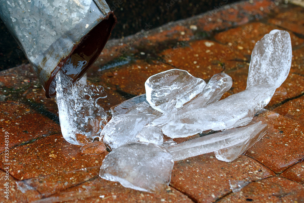 Drain pipe and melting ice, wet sidewalk. Ice in drainpipe, ice dams ...