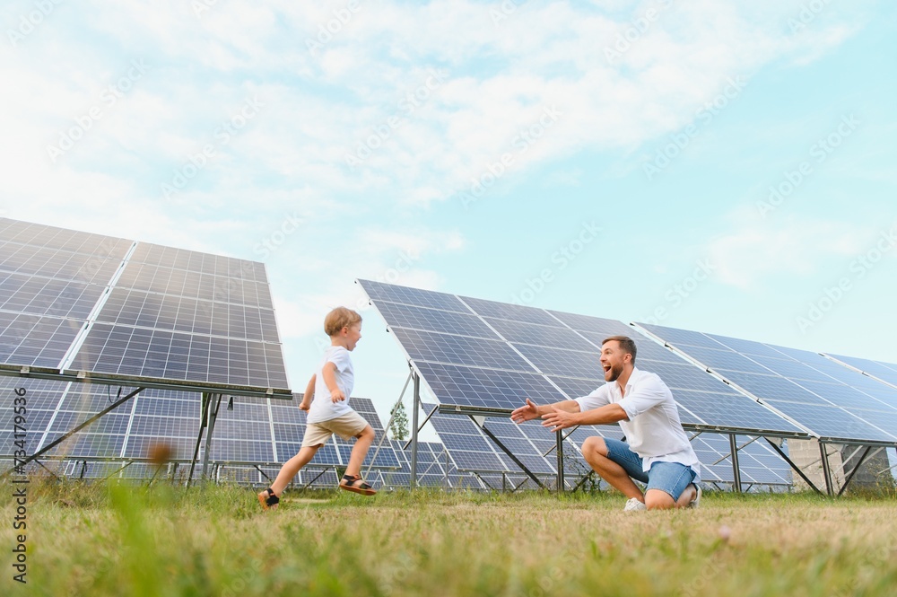 Smiling father and his little child on background of solar panels ...