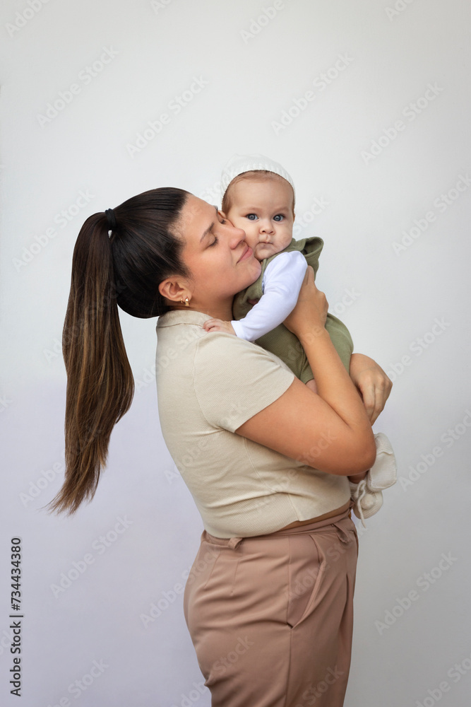 Madre sonriendo cargando a su bebé delante de un fondo blanco ...